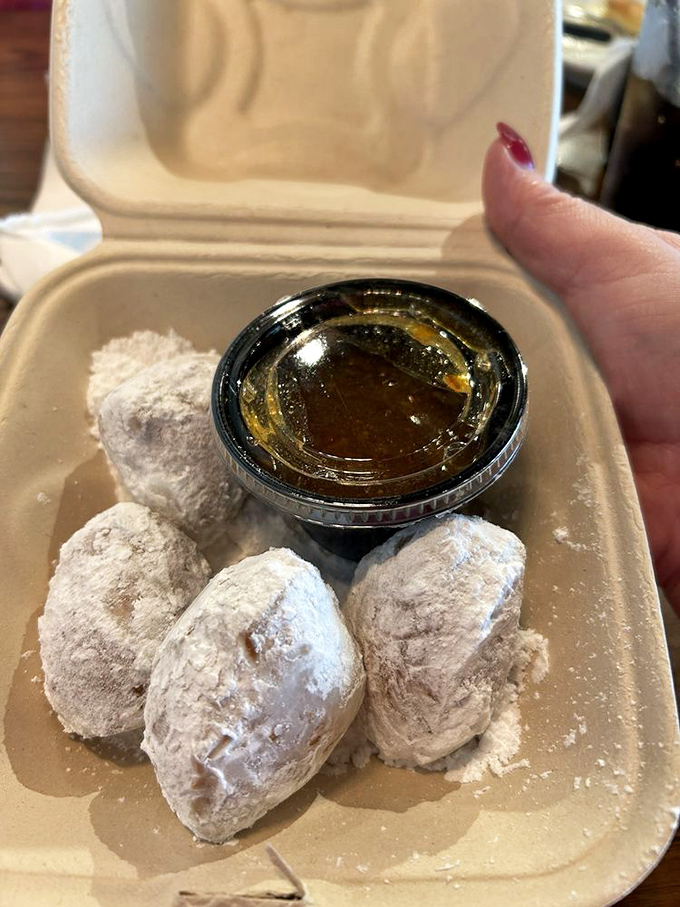 Biscuit Beignets dusted with powdered sugar and served with honey—little clouds of Southern heaven that make donuts question their life choices.