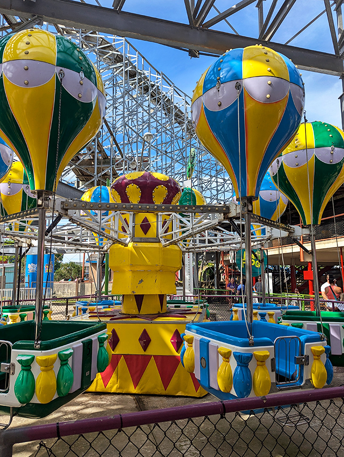 These hot air balloon-themed cars pirouette like mechanical dancers. The worn paint tells stories of decades of smiling children spinning into joyful dizziness.