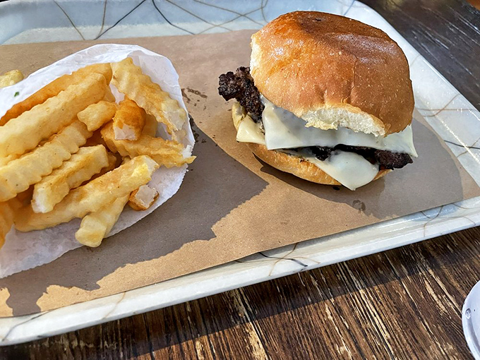 A burger that deserves its own ZIP code, flanked by fries so perfectly golden they could qualify for Olympic medals.