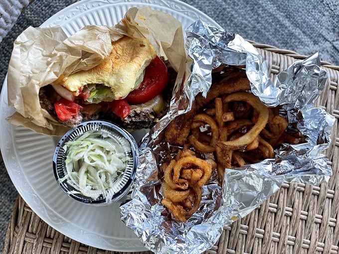 The classic American trinity: a perfectly dressed burger, crispy onion rings, and coleslaw—served unpretentiously on a plate that lets the food shine.