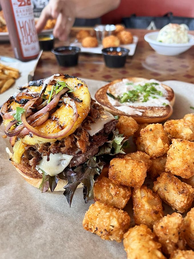 A burger that's clearly been hanging out with the barbecue crowd, topped with what appears to be pulled pork. Tots: the unsung heroes of side dishes.