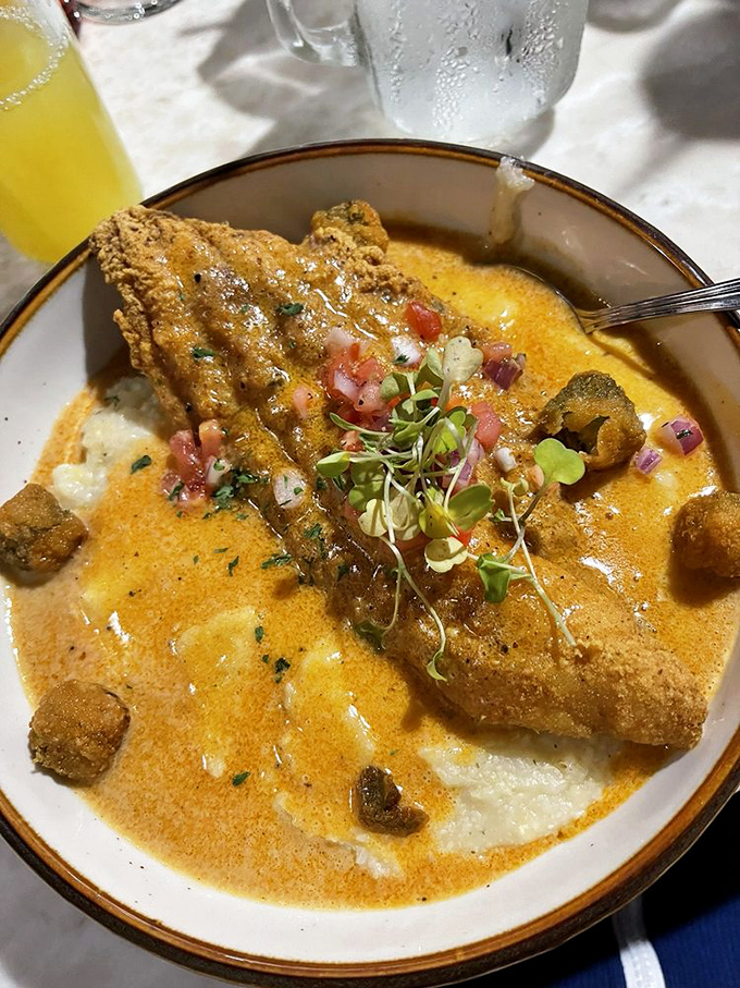 Crispy catfish lounging on a bed of creamy grits with a saucy attitude&mdash;like the main character in a delicious Southern novel.