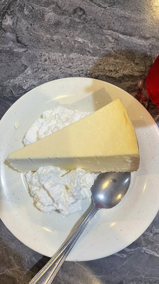 Cheesecake so smooth it could talk its way out of a parking ticket, paired with whipped cream for moral support.