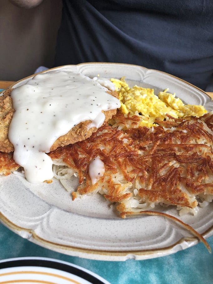 Country gravy cascading over crispy chicken fried steak, with those famous hash browns standing guard. Comfort food that hugs your soul.