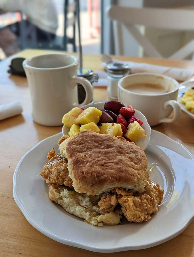 Fried chicken nestled between a golden biscuit with fresh fruit on the side&mdash;because balance is important, even in indulgence.