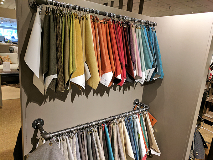 A rainbow of fabric possibilities hanging like well-organized promises. Your furniture's future wardrobe awaits your decision.