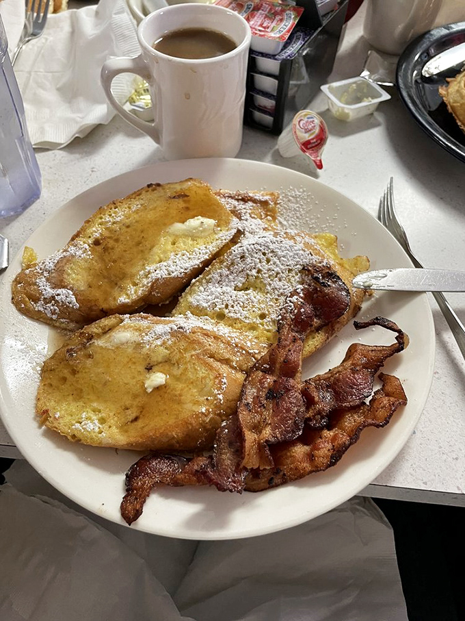 The holy trinity of breakfast bliss: golden French toast, bacon with the perfect wave, and coffee that promises to jumpstart your day.