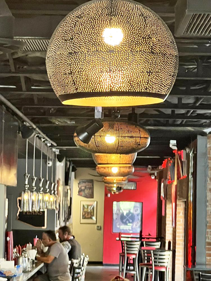 The pendant lights hang like modern art installations, casting a warm glow that makes everyone look good, even with burger sauce on their chin.