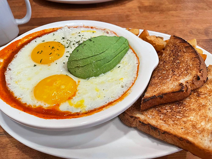 These eggs aren't just sunny-side up&mdash;they're floating in a spicy tomato bath with avocado playing lifeguard. Toast stands ready for dipping duty.