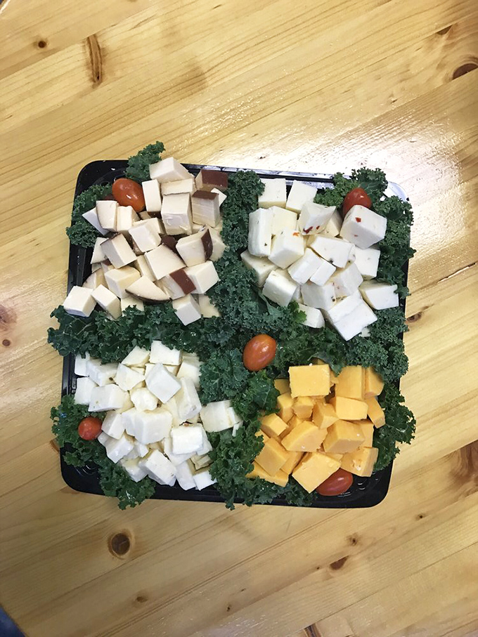 Four varieties of cheese, thoughtfully cubed and separated by kale with cherry tomato accents. This isn't just food; it's edible art for the discerning palate.