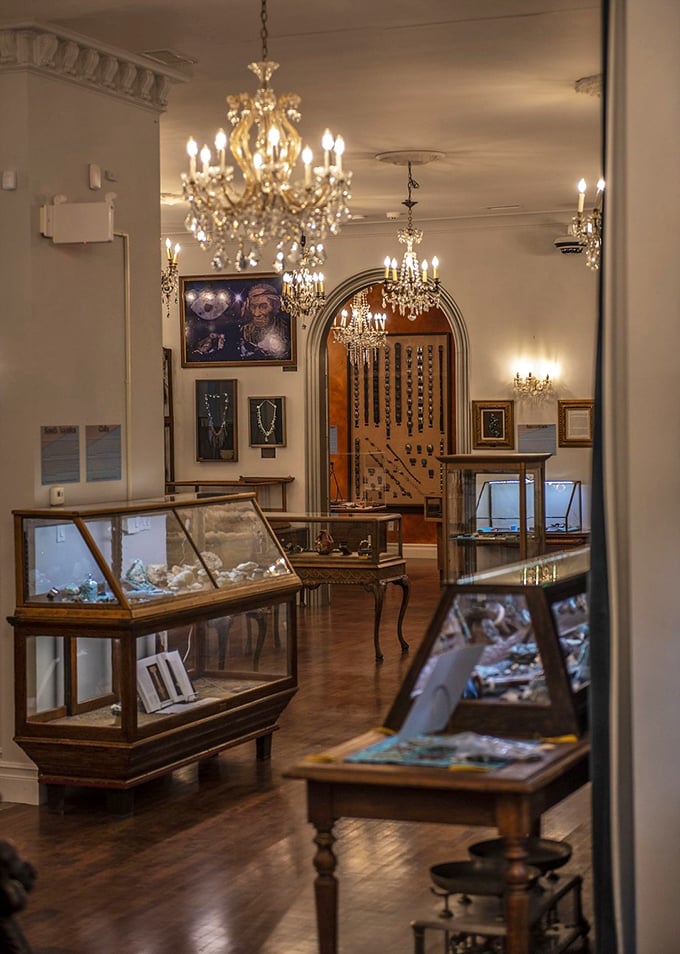 Museum magic happens in rooms like this, where elegant display cases under sparkling chandeliers invite visitors to lose themselves in a world of gemstone wonder.