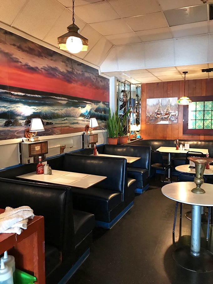 Navy blue booths stand at attention beneath dramatic ocean art, creating a dining room that feels like a cozy captain's quarters.
