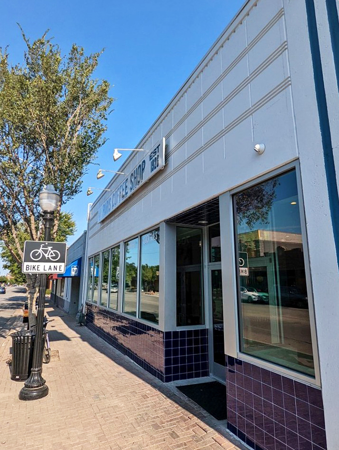 Paris Coffee Shop's pristine white exterior and blue tile base offer a clean, classic look. The bike lane sign suggests you might need exercise after their pancakes!