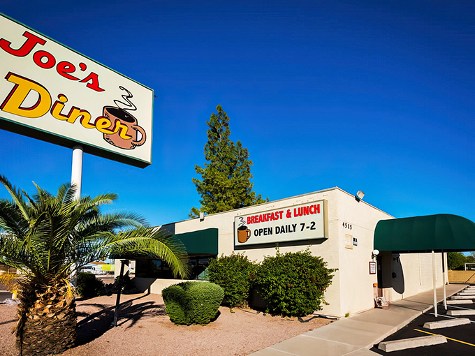 The unassuming exterior of Joe's Diner stands like a beacon of breakfast hope in Phoenix, promising hash brown nirvana behind that green awning.