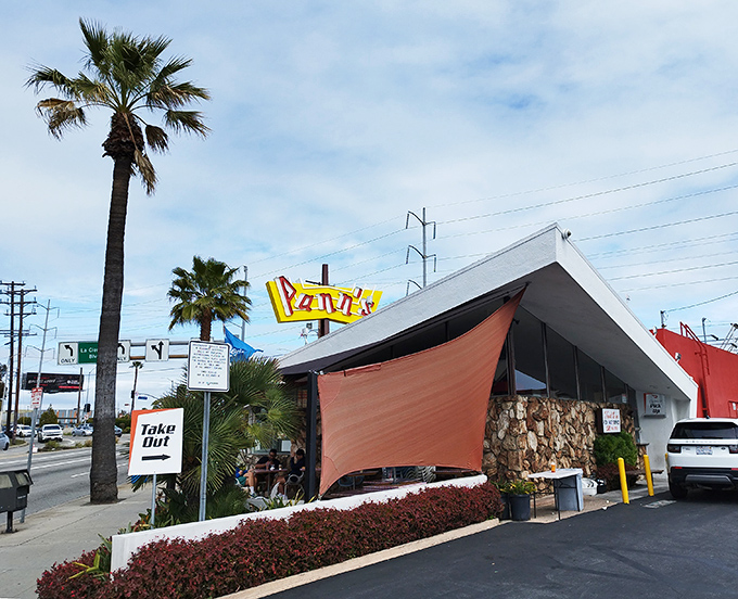 The iconic angular roof and neon sign of Pann's stands like a mid-century time machine, palm trees swaying as if to say "classic California awaits inside."