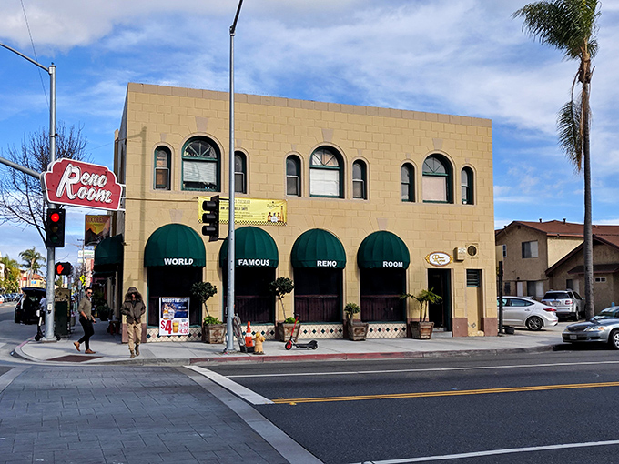 The tan facade with those iconic green awnings spelling "WORLD FAMOUS RENO ROOM" is like a beacon for thirsty travelers on East Broadway.