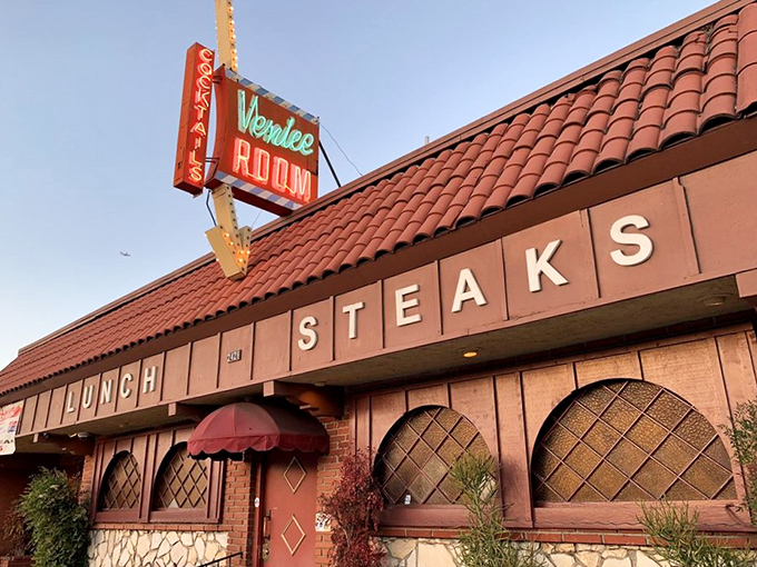 The Venice Room's iconic turquoise and red exterior stands as a defiant time capsule in Monterey Park, beckoning carnivores with its straightforward promise: COCKTAILS and STEAKS.