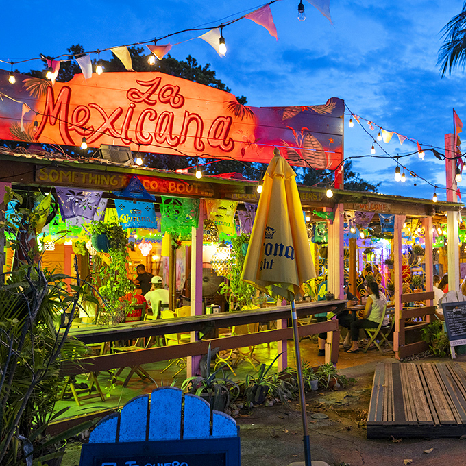 Welcome to paradise! La Mexicana's charming outdoor entrance, with its colorful umbrellas and lush greenery, promises a tropical escape from everyday life.
