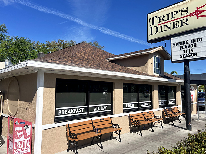 The welcoming exterior of Trip's Diner beckons hungry Tampa locals with its no-nonsense sign and cozy bench seating for the inevitable weekend wait.
