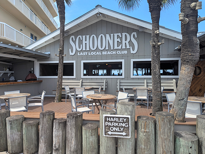 Schooners proudly declares itself "The Last Local Beach Club" &ndash; a weathered wooden oasis where palm trees and Harley parking signs set the perfect Florida mood.