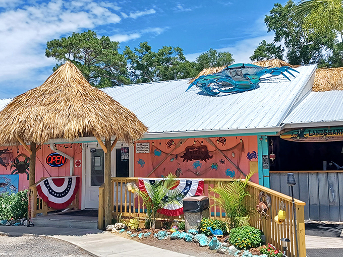 The coral-colored exterior of Kathi's Krab Shack beckons like a tropical mirage, complete with thatched roof and a giant crab announcing seafood paradise awaits.