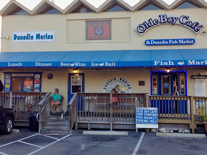 The unassuming entrance to seafood paradise. Olde Bay Caf&eacute;'s blue awning and weathered wooden deck promise authentic Florida dining without pretense.