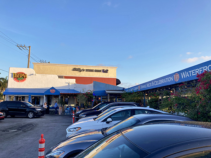 The sun-drenched exterior of Taverna Opa beckons like a Mediterranean mirage amid Florida's concrete jungle. Blue accents promise Greek delights inside.
