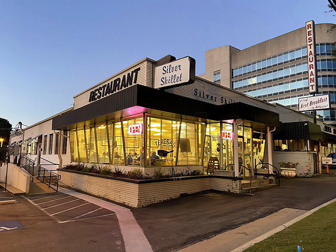 The Silver Skillet's mid-century exterior glows like a time capsule at dusk, beckoning hungry travelers with promises of Southern comfort and nostalgia.