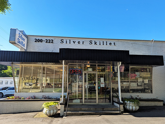 The Silver Skillet stands proudly against Atlanta's blue sky, its vintage sign a beacon for hungry souls seeking breakfast salvation in the city's bustling landscape.