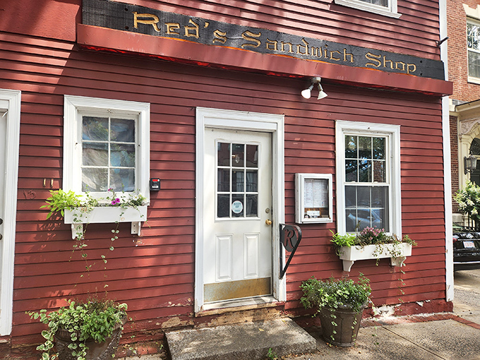 The iconic crimson colonial exterior of Red's Sandwich Shop stands as proudly in Salem as Paul Revere once did, beckoning hungry visitors with historical charm.