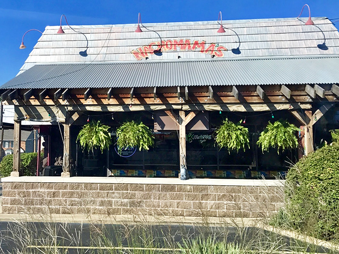 The vibrant exterior of Nachomama's beckons with colorful pepper artwork and inviting picnic tables. Tex-Mex paradise awaits behind that neon glow.