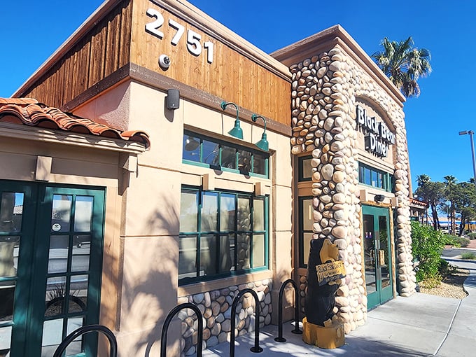 The rustic stone-and-timber facade of Black Bear Diner stands like a mountain lodge mirage in the Nevada desert, promising comfort food salvation to weary travelers.