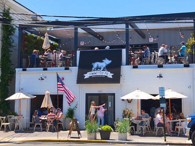 The Committed Pig's charming white exterior with rooftop dining is like finding the VIP section of Jersey Shore dining—complete with American flag and umbrellas for those who prefer shade with their indulgence.