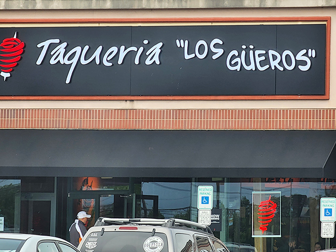 The iconic black sign with white lettering and red spiral logo beckons hungry travelers like a lighthouse for those lost in a sea of mediocre Mexican food.