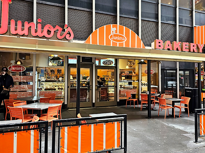 The iconic orange and white fa&ccedil;ade of Junior's glows like a beacon for cheesecake pilgrims, promising sweet salvation in a busy city.