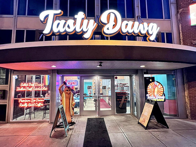The neon glow of Tasty Dawg's storefront beckons like a lighthouse for the hungry, complete with a hot dog mascot standing guard at the entrance.