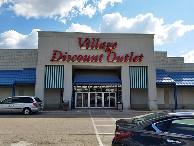 The iconic red lettering of Village Discount Outlet beckons bargain hunters like a retail lighthouse guiding ships to treasure-filled shores.