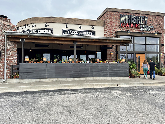 Rustic brick meets modern charm at Whiskey Cake's inviting exterior. The patio planters hint at the farm-to-table philosophy waiting inside.