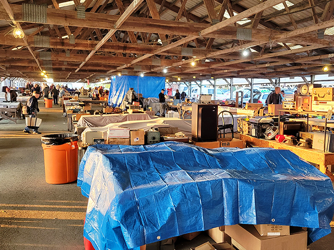 Treasure hunters navigate the cavernous barn-like structure where decades of history await discovery beneath rustic wooden beams and warm lighting.