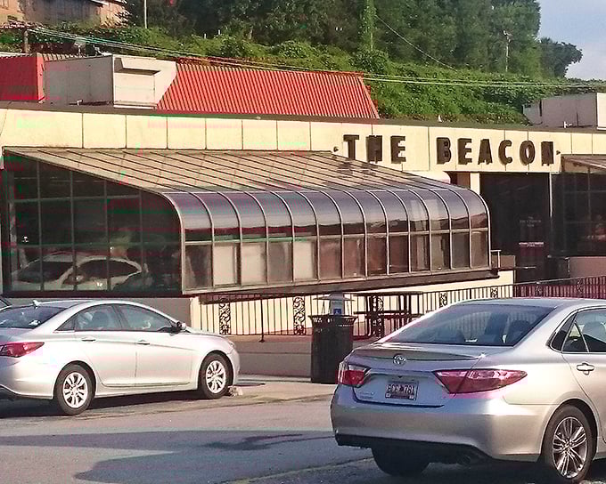 The iconic cream-colored exterior of The Beacon, with its bold signage and American flags, stands as Spartanburg's culinary lighthouse guiding hungry travelers home.