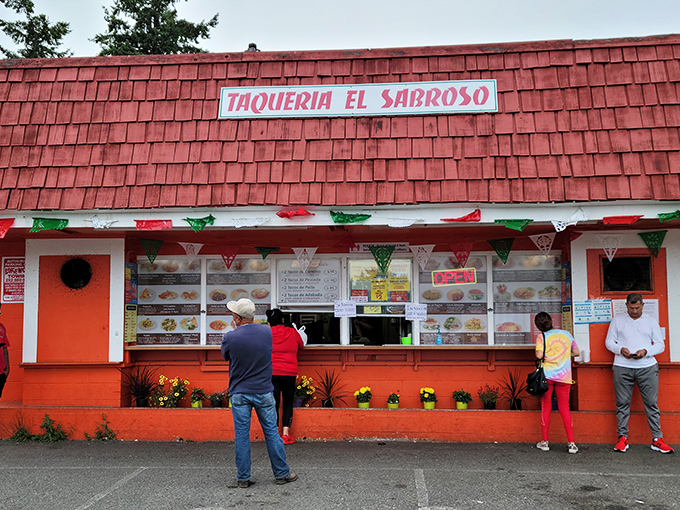 The red-roofed taqueria stands out like a culinary lighthouse, beckoning hungry travelers with its vibrant orange walls and festive papel picado banners.
