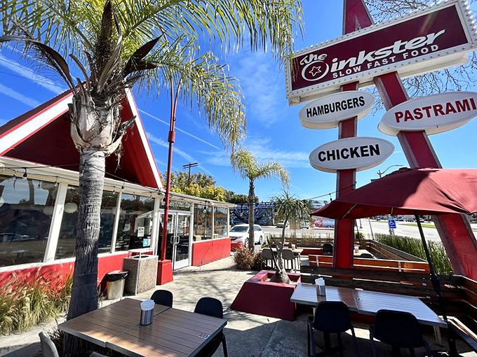 The iconic A-frame building beckons like a red-roofed temple of deliciousness, complete with retro signage that doesn't mince words: hamburgers, pastrami, chicken.