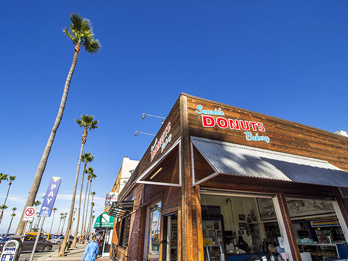 Palm trees stand sentry outside Seaside Donuts' wooden facade, nature's exclamation points announcing: "Something delicious happens here!"