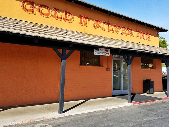 The iconic orange exterior with glowing red signage announces itself like Vegas neon for the hungry. No pretension, just breakfast promise.