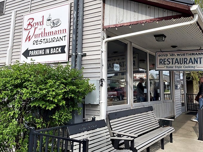 The unassuming exterior of Boyd & Wurthmann Restaurant, where that weathered bench has heard more food stories than most food critics. Culinary treasures await inside.