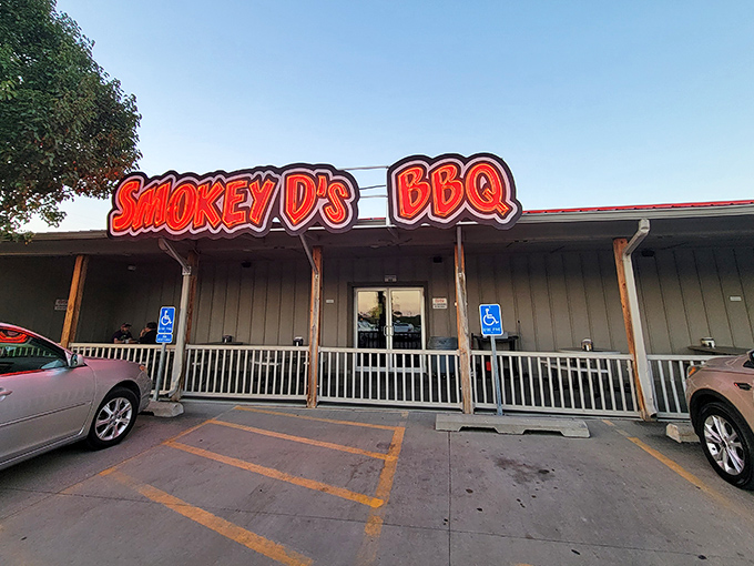 The neon-red sign of Smokey D's BBQ glows like a beacon for hungry souls, promising salvation through smoke and meat in Des Moines.