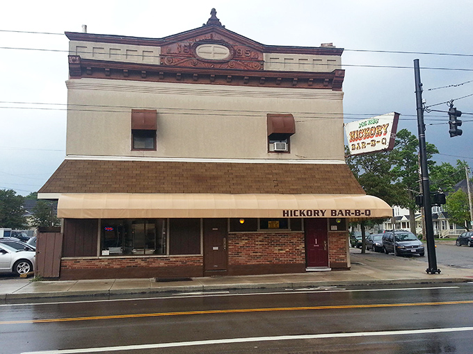 The historic facade of Hickory Bar-B-Q stands like a time capsule on Dayton's streets, its burgundy awning beckoning hungry travelers like a smoky siren call.
