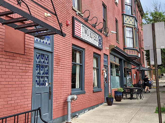 The historic brick facade of Two Rivers Brewing Company glows with warmth, its American flag-inspired sign beckoning hungry travelers like a culinary lighthouse.