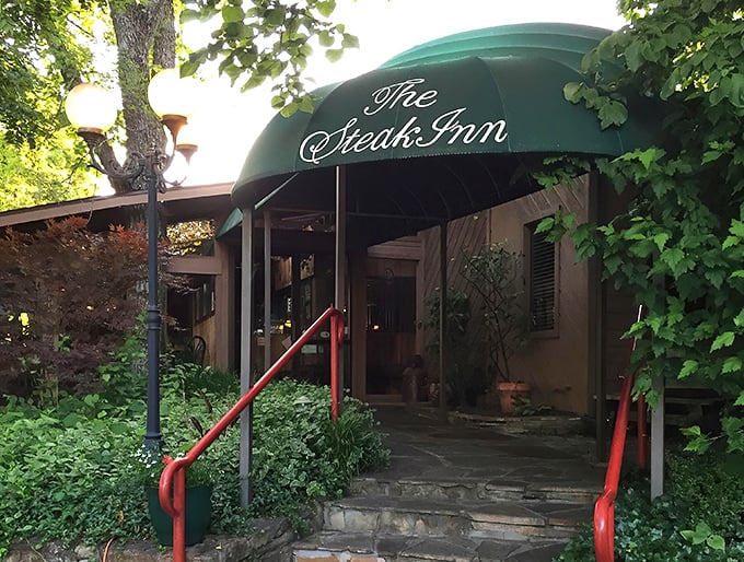 The iconic green awning and red railings of The Steak Inn welcome hungry travelers like a beacon in the Ozark wilderness.