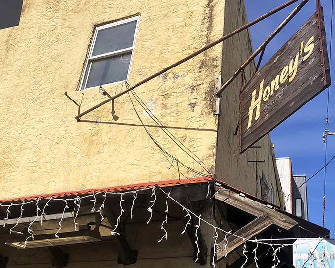 The weathered wooden sign against that sunny yellow exterior is like a beacon for breakfast pilgrims. Honey's promises comfort before you even step inside.